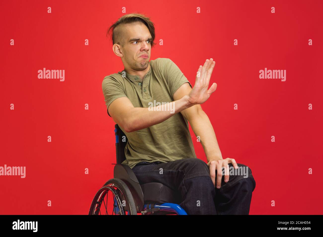 Rejecting, stopping. Caucasian young disabled man's portrait on red ...