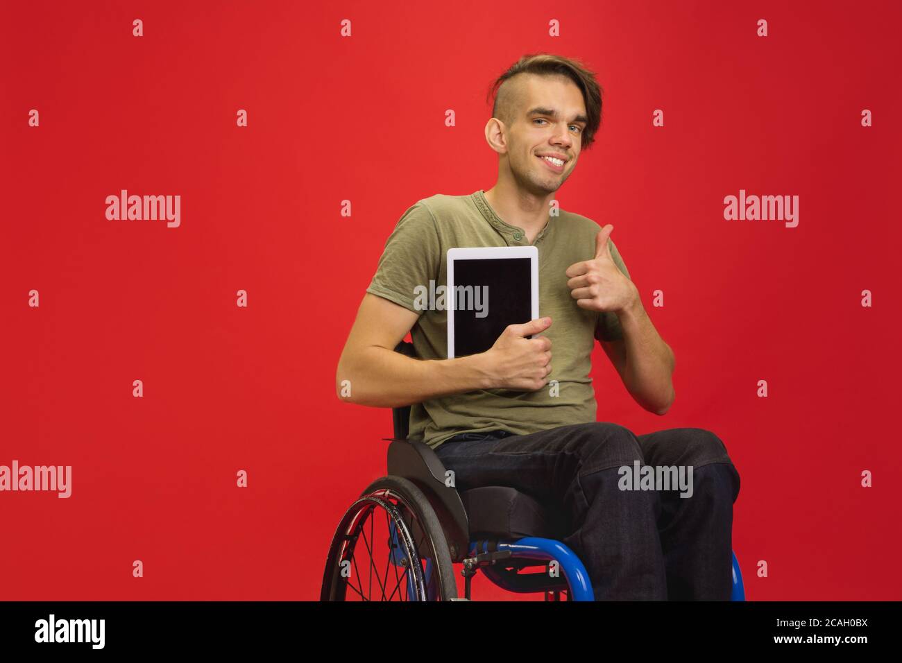 Holding tablet, thumb up. Caucasian young disabled man's portrait on ...