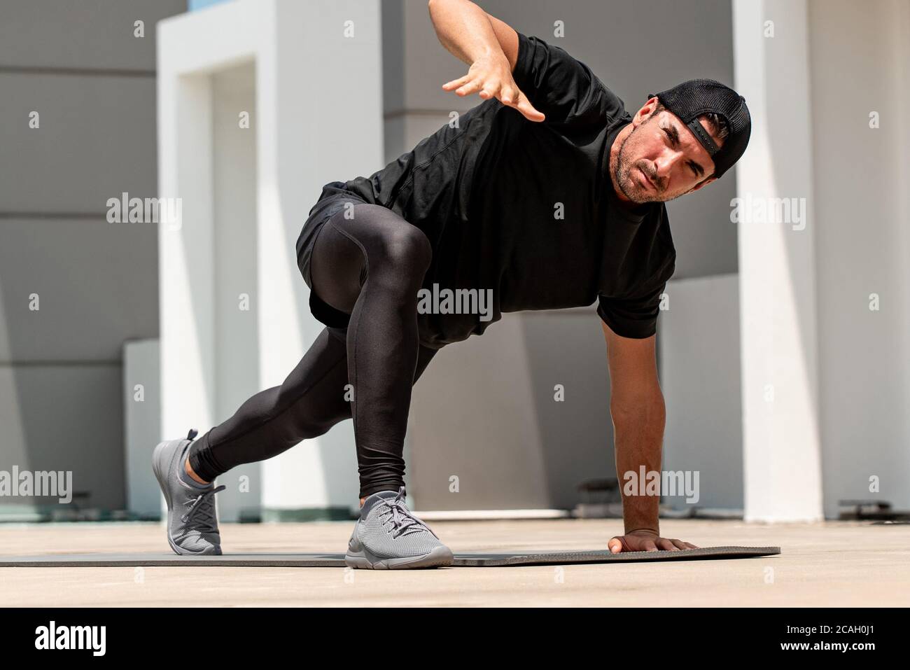 Fit handsome sports man warming up with spider lunge exercise outdoors ...