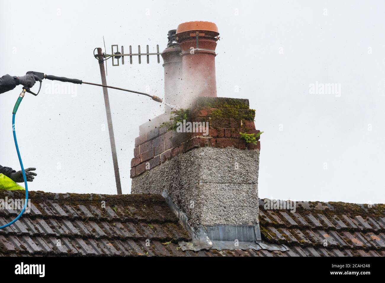 Man power washing a chimney stack and roof to remove dirt, moss and ...