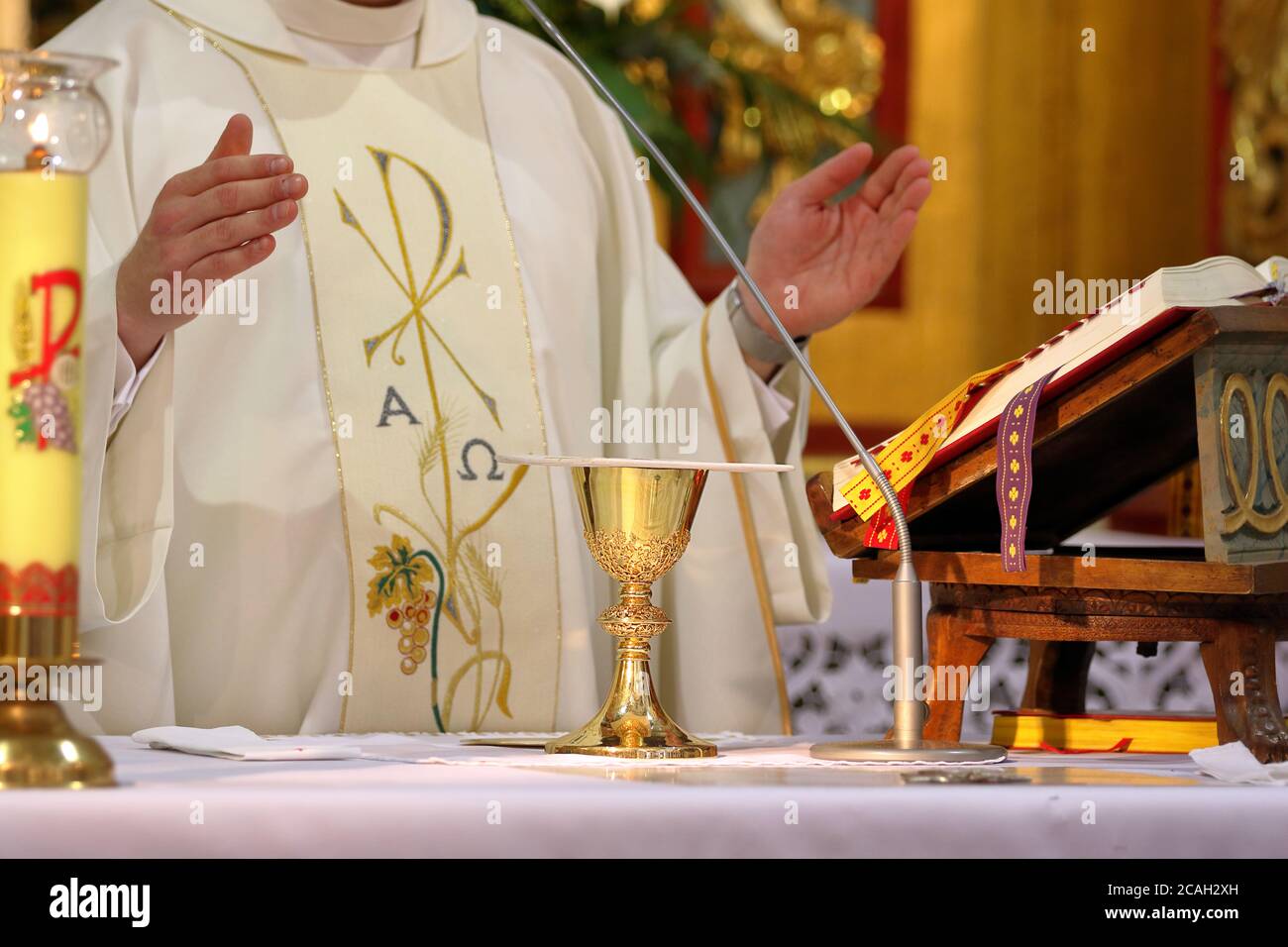 Chalice on the altar and priest celebrating mass in the background and ...