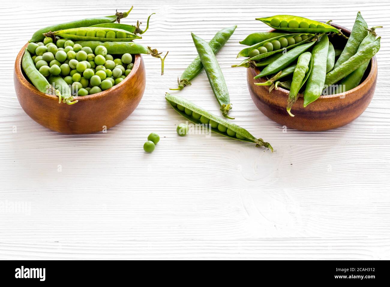 Set of green pea pods in wooden bowl on kitchen table desk Stock Photo ...