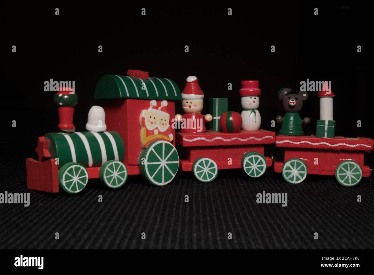 Red children`s Christmas train on a black background. New Year's toy ...