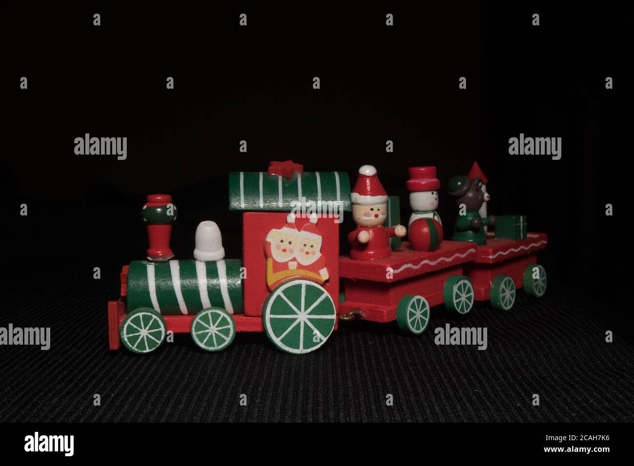 Red children`s Christmas train on a black background. New Year's toy ...