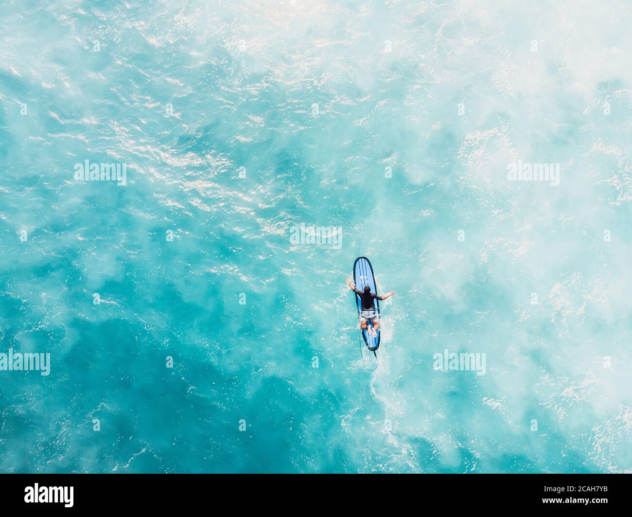 Aerial view of surfer on surfboard rowing in blue ocean. Top view Stock ...