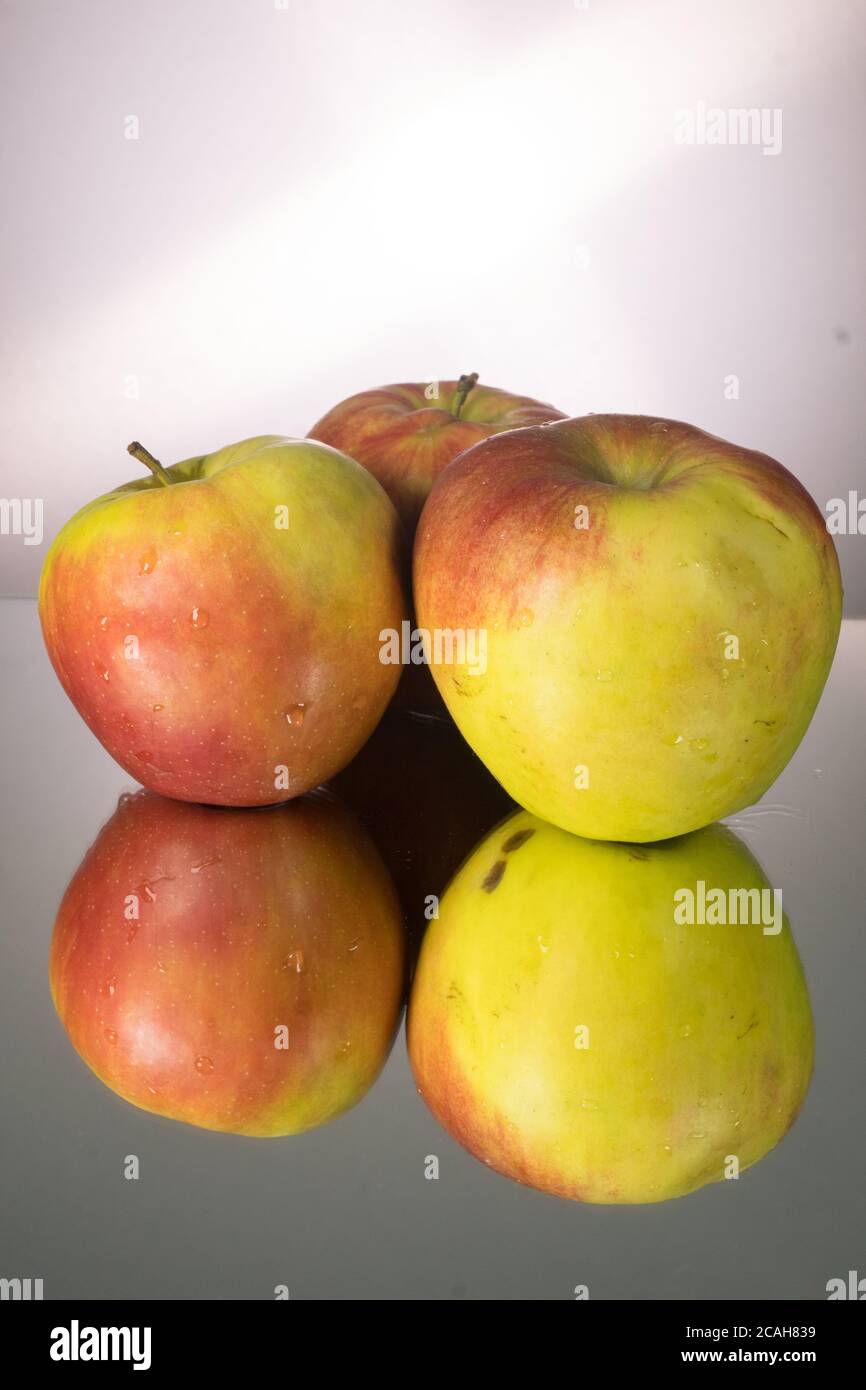 Three red apple on mirroring table. Vertical image with copy space ...