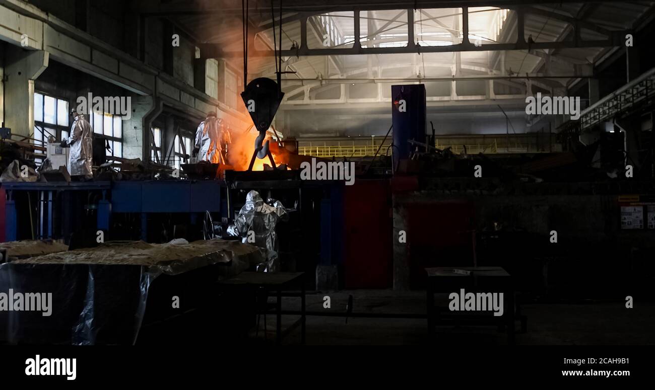 Smelting metal in a metallurgical plant. Liquid iron from metal ladle ...