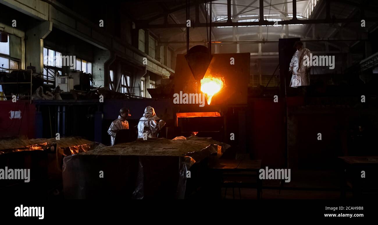 Smelting metal in a metallurgical plant. Liquid iron from metal ladle ...