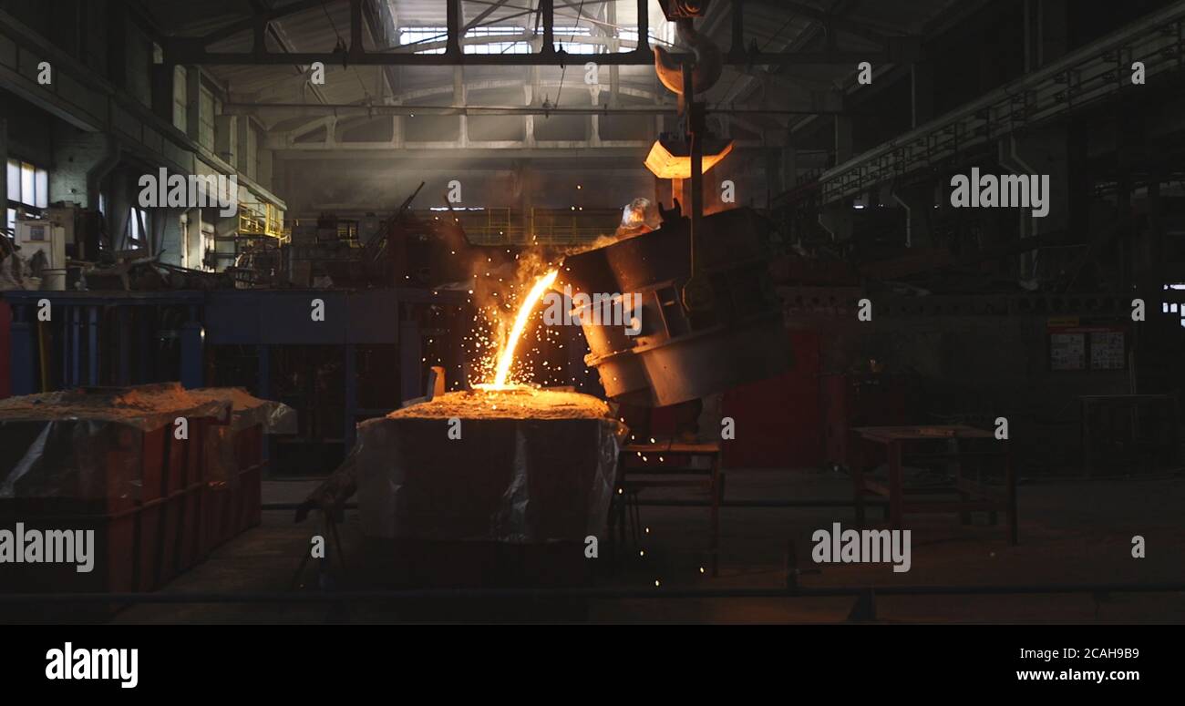 Smelting metal in a metallurgical plant. Liquid iron from metal ladle ...