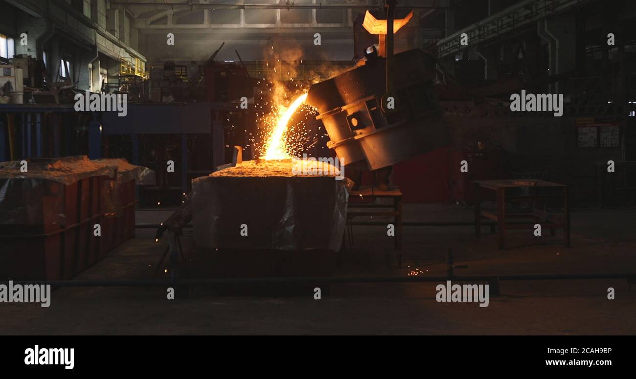 Smelting metal in a metallurgical plant. Liquid iron from metal ladle ...