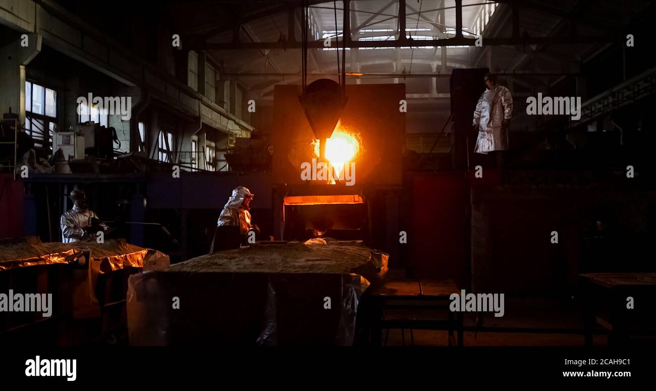 Smelting metal in a metallurgical plant. Liquid iron from metal ladle ...