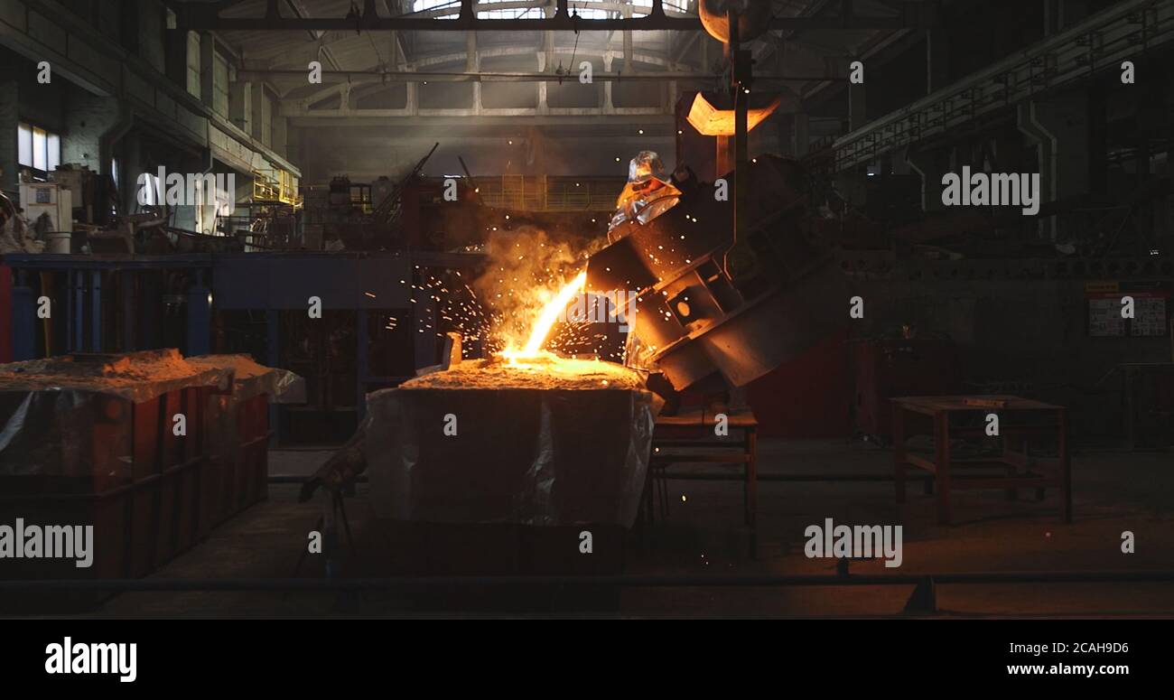 Smelting metal in a metallurgical plant. Liquid iron from metal ladle ...
