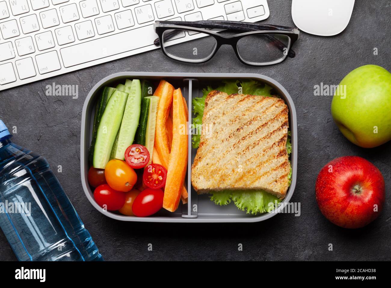 Healthy lunch box with sandwich and vegetables on office table. Top ...