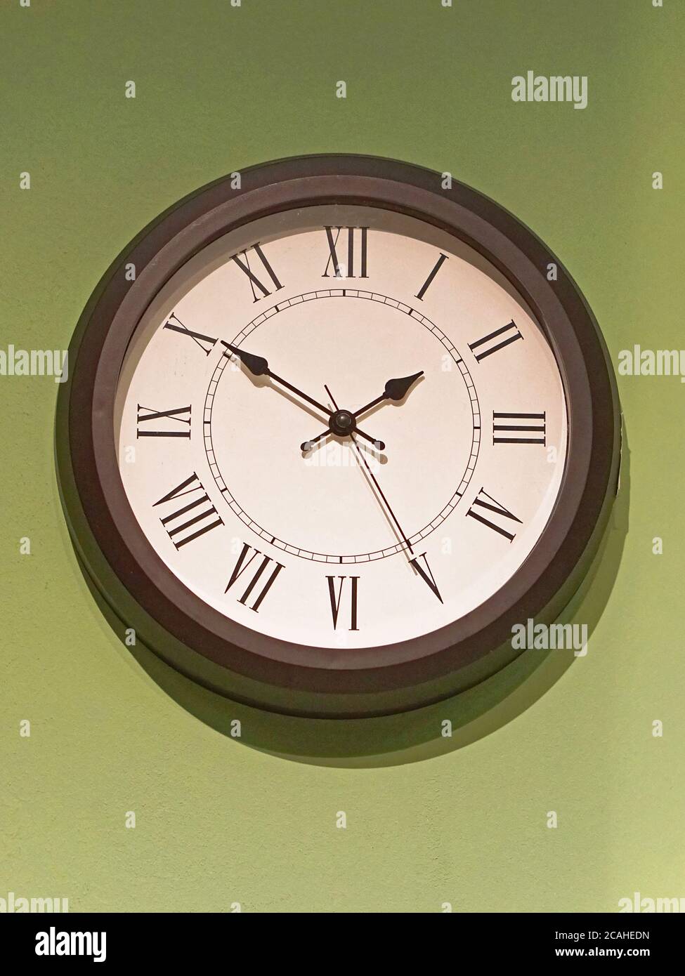 Big old clock with Roman numbers at green wall Stock Photo - Alamy