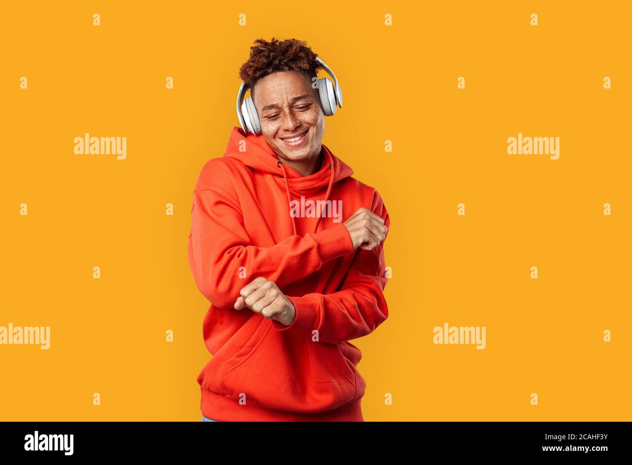 Freestyle. Mulatto freckled guy in hoodie and headphones standing ...