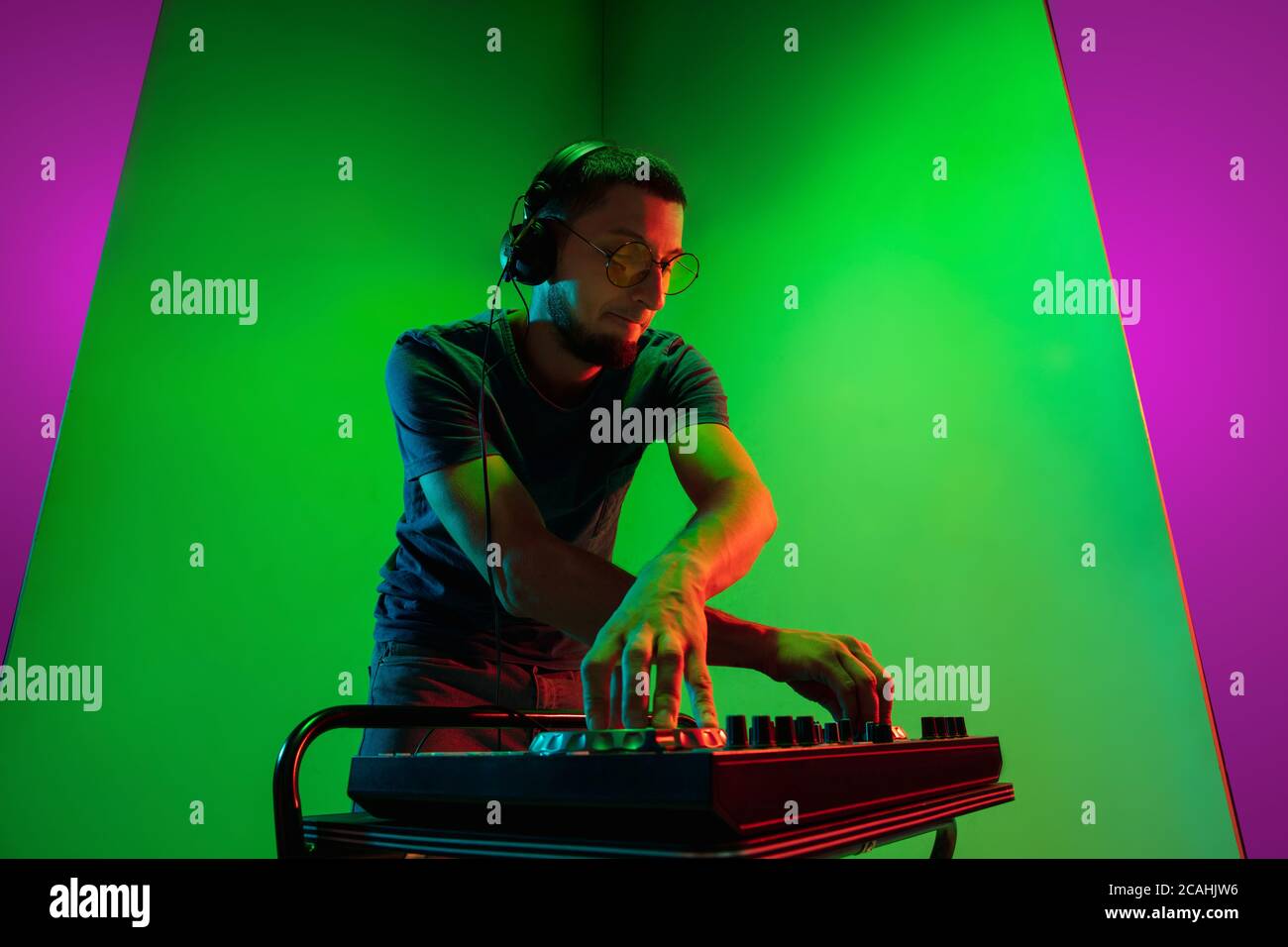 Art. Young caucasian musician in headphones performing on bicolored ...