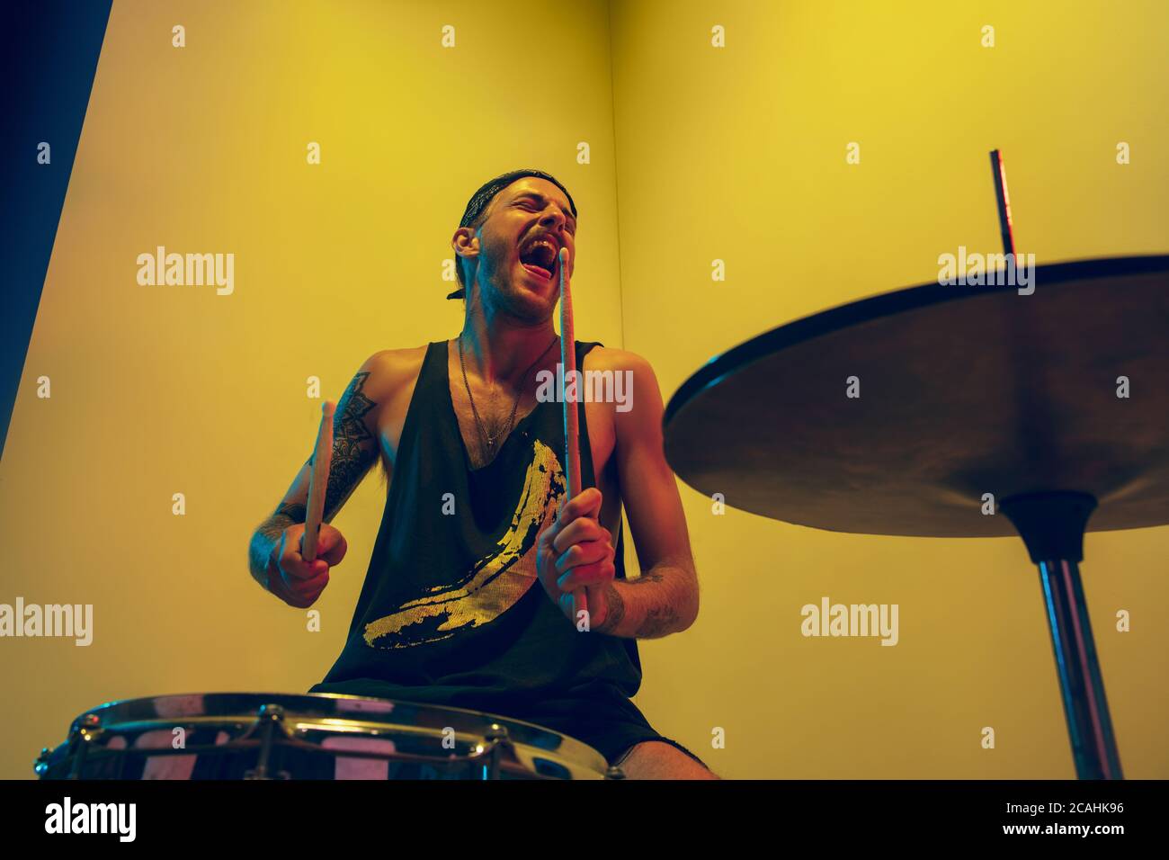 Summer vibe. Young musician with drums performing on yellow background ...
