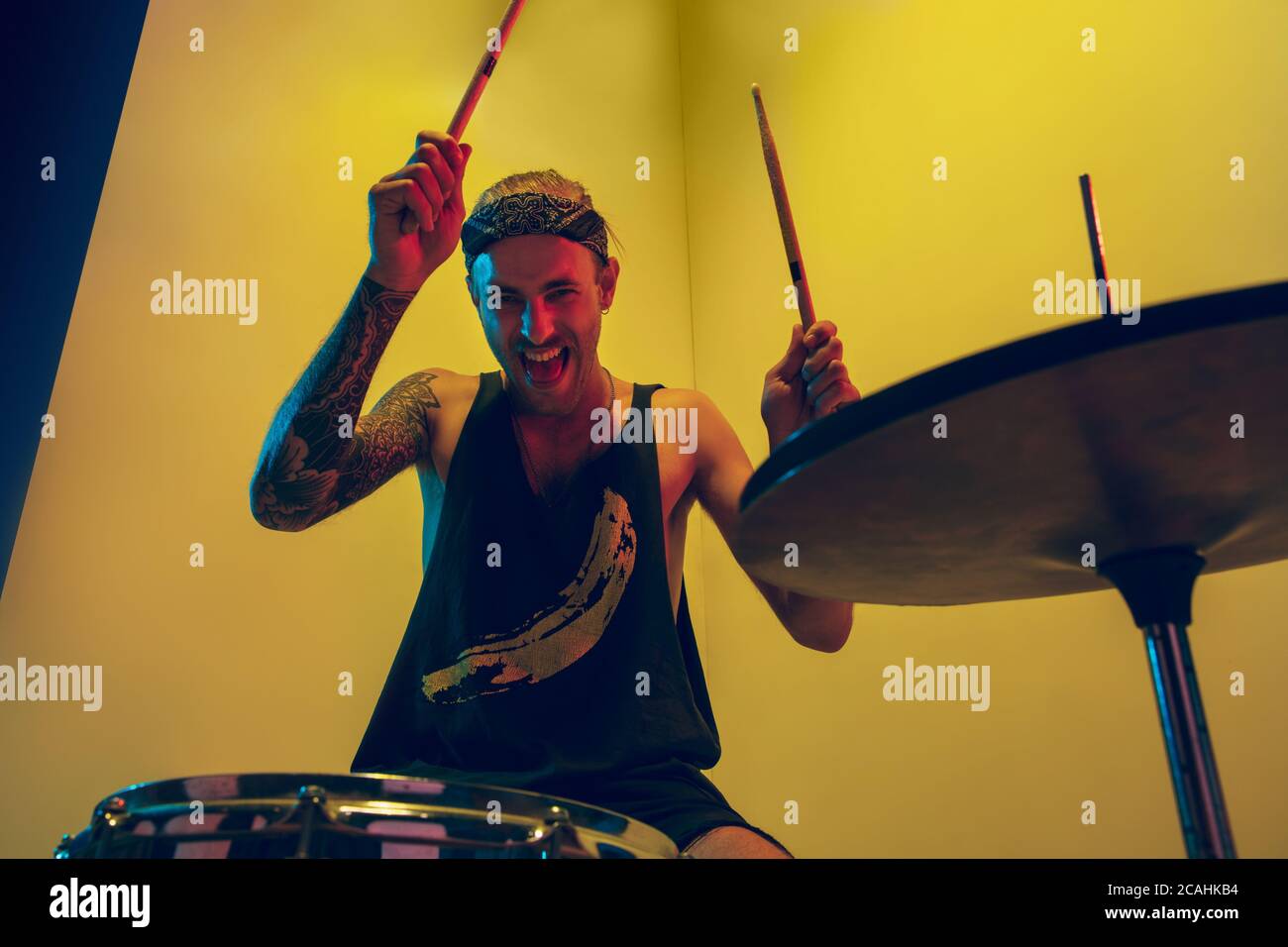 Summer vibe. Young musician with drums performing on yellow background ...