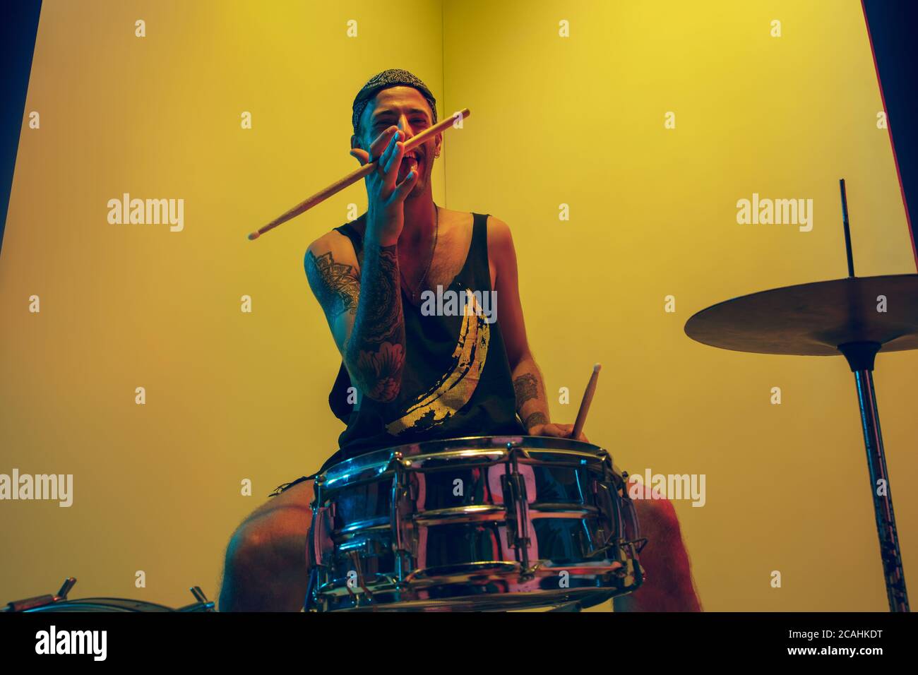 Summer vibe. Young musician with drums performing on yellow background ...