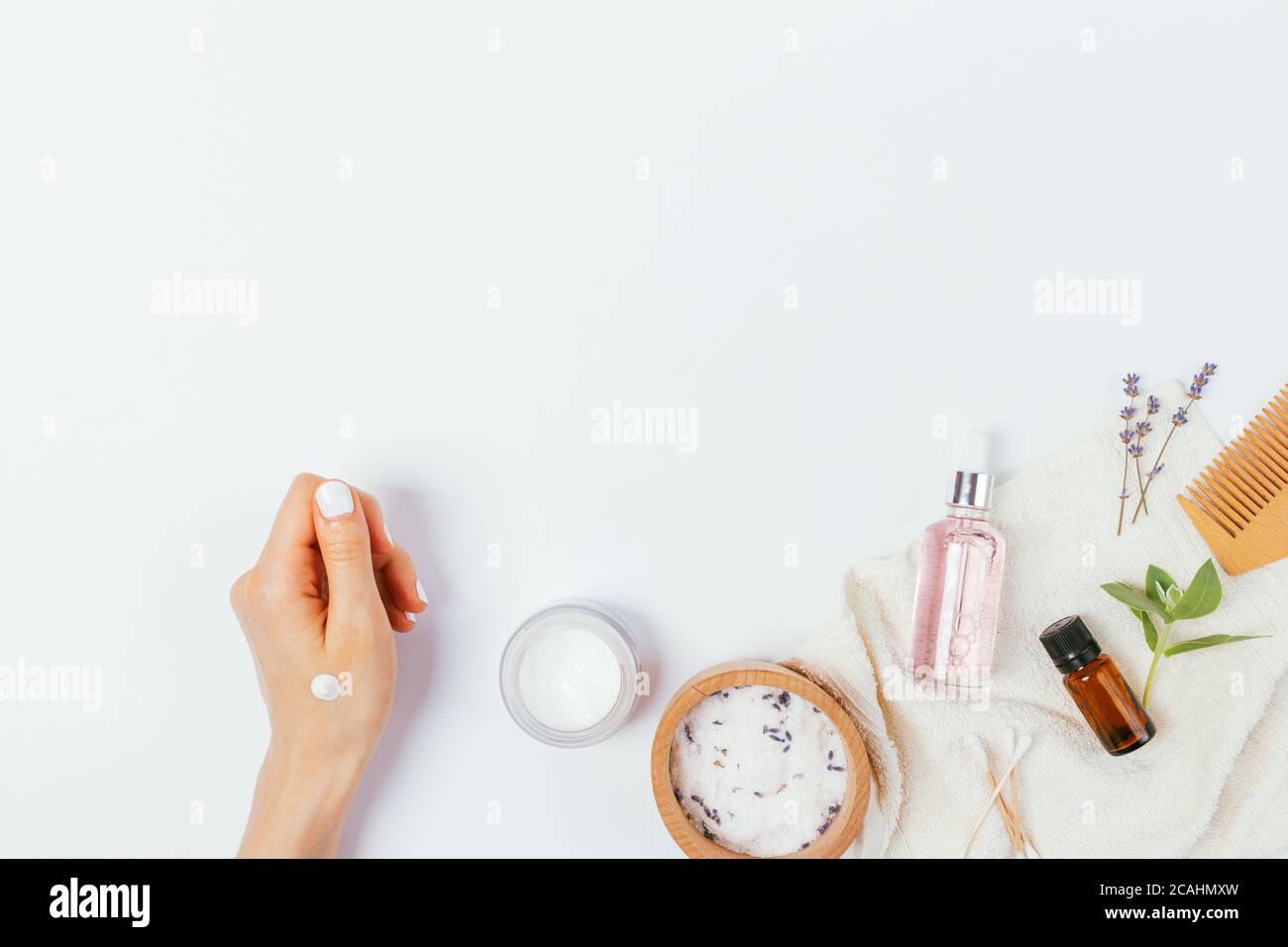 Female hand applying moisturizer next to cosmetic skin care products ...