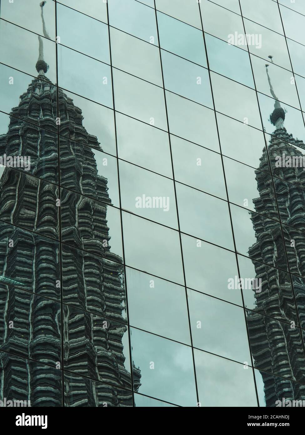 Vertical shot of high-rise buildings reflecting in a glass facade of a ...
