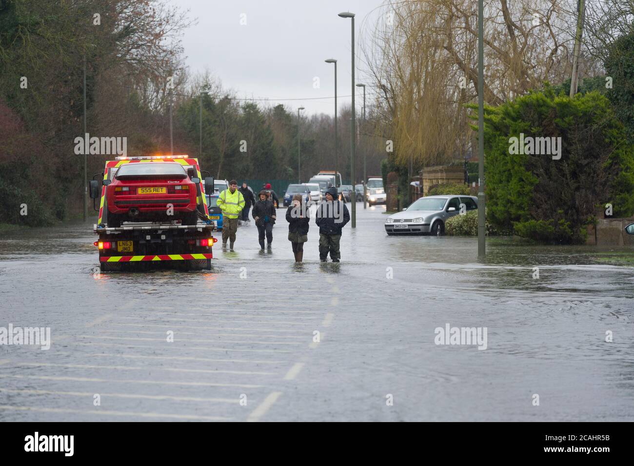People walking through flood waters along Chertsey Lane, Egham Hythe ...