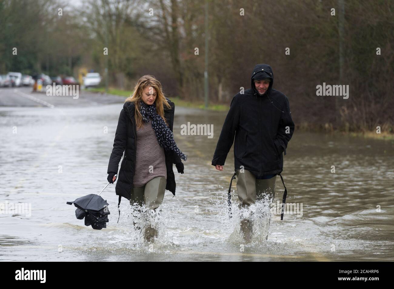 People walking through flood waters along Chertsey Lane, Egham Hythe ...