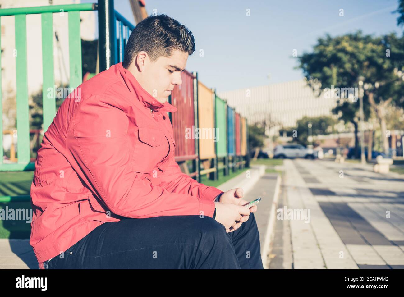 Caucasian male sitting outside and texting on his smartphone Stock ...
