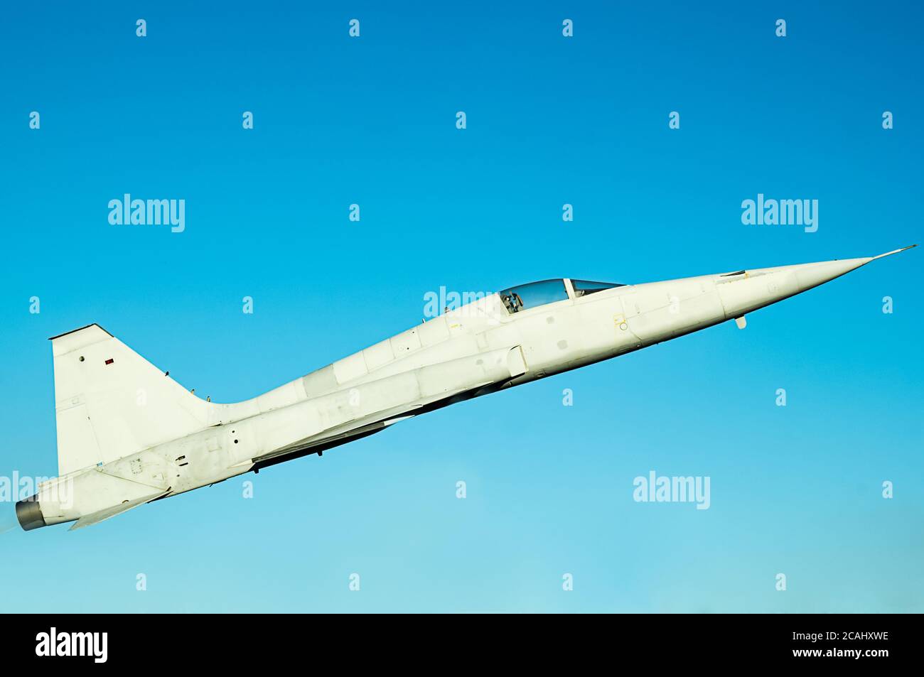 White fighter plane on a clear blue sky background Stock Photo - Alamy