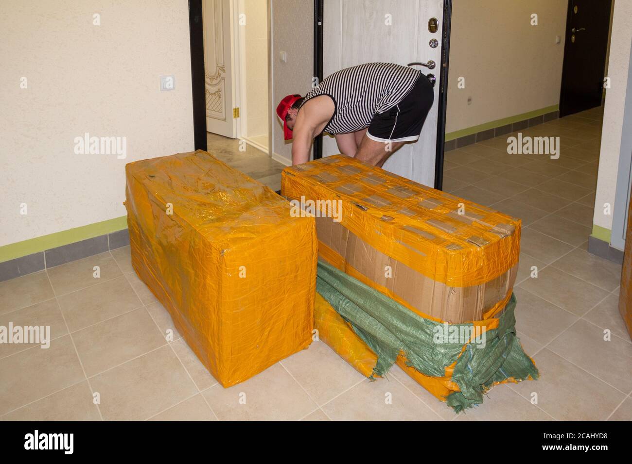 a young guy unpacks large yellow parcels from China in the apartment ...