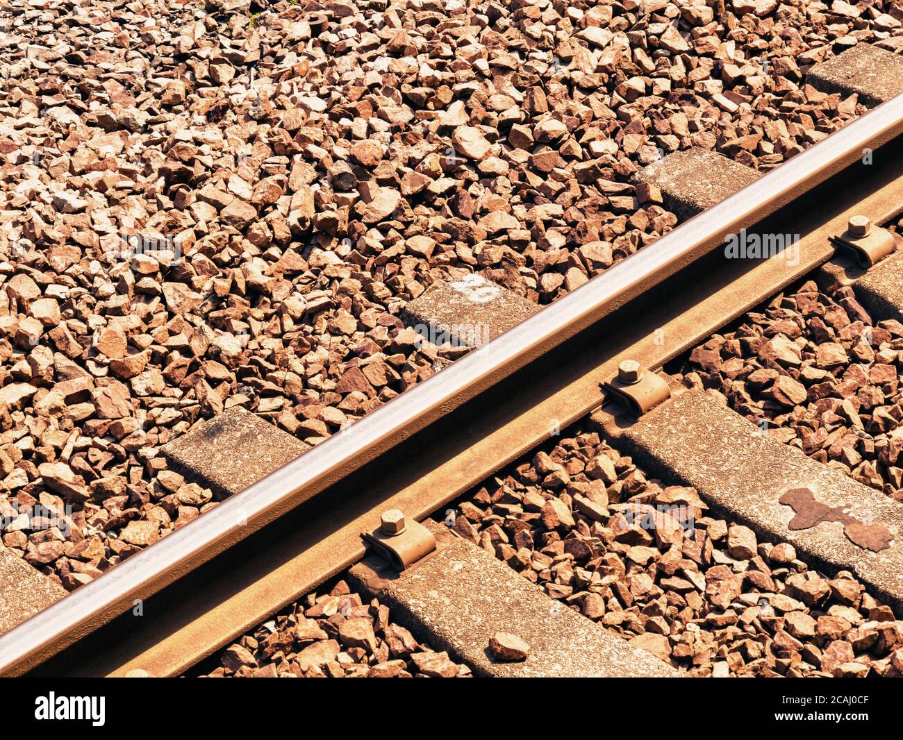 Closeup shot of a metal railing surrounded by rocks on a train track ...