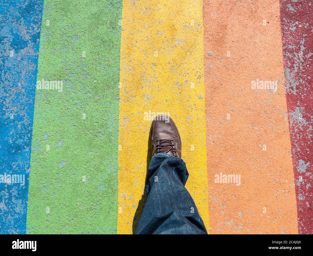 Top view of a male foot on a rainbow colored sidewalk- LGBT concept ...