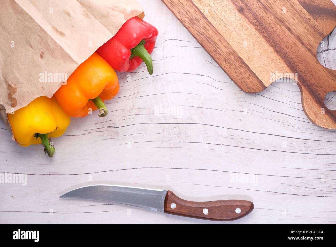 Yellow orange and red capsicum with chopping board on table Stock Photo ...