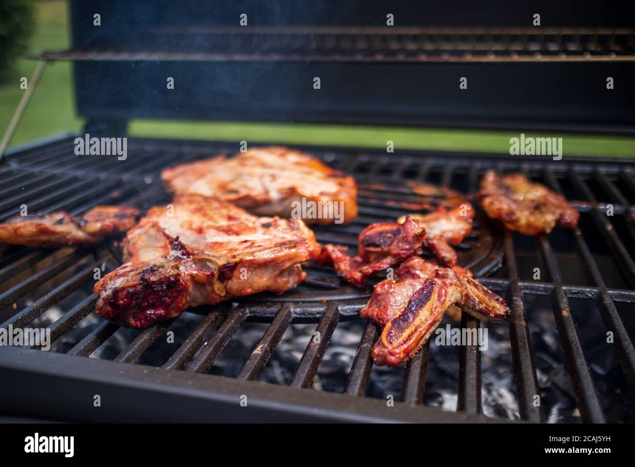 Home barbecue with charcoal in the backyard grilling steaks and other ...