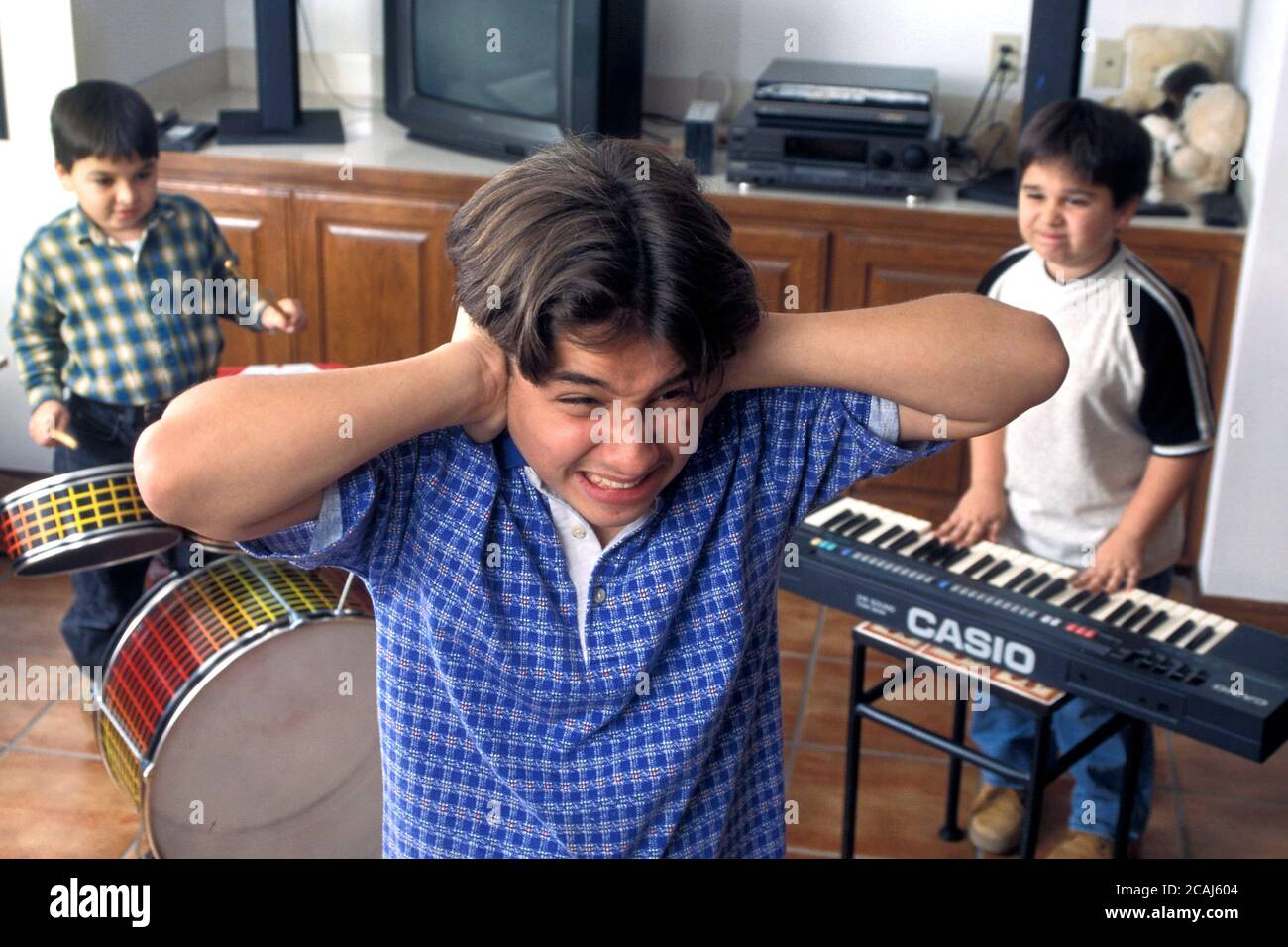 Young Hispanic boy covers ears with his hands to shut out noise from ...