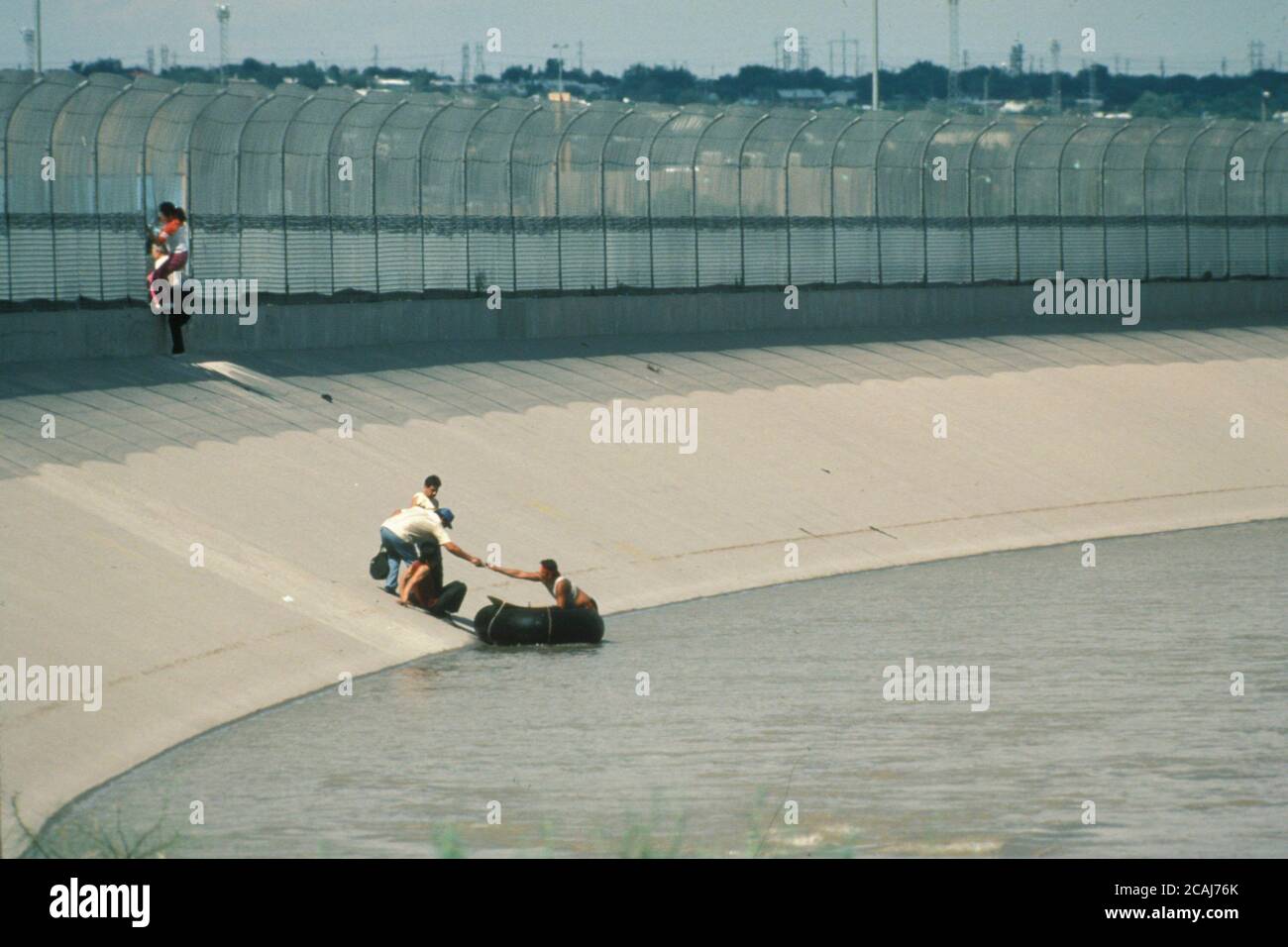Small group of immigrants cross the channelized Rio Grande River, the ...