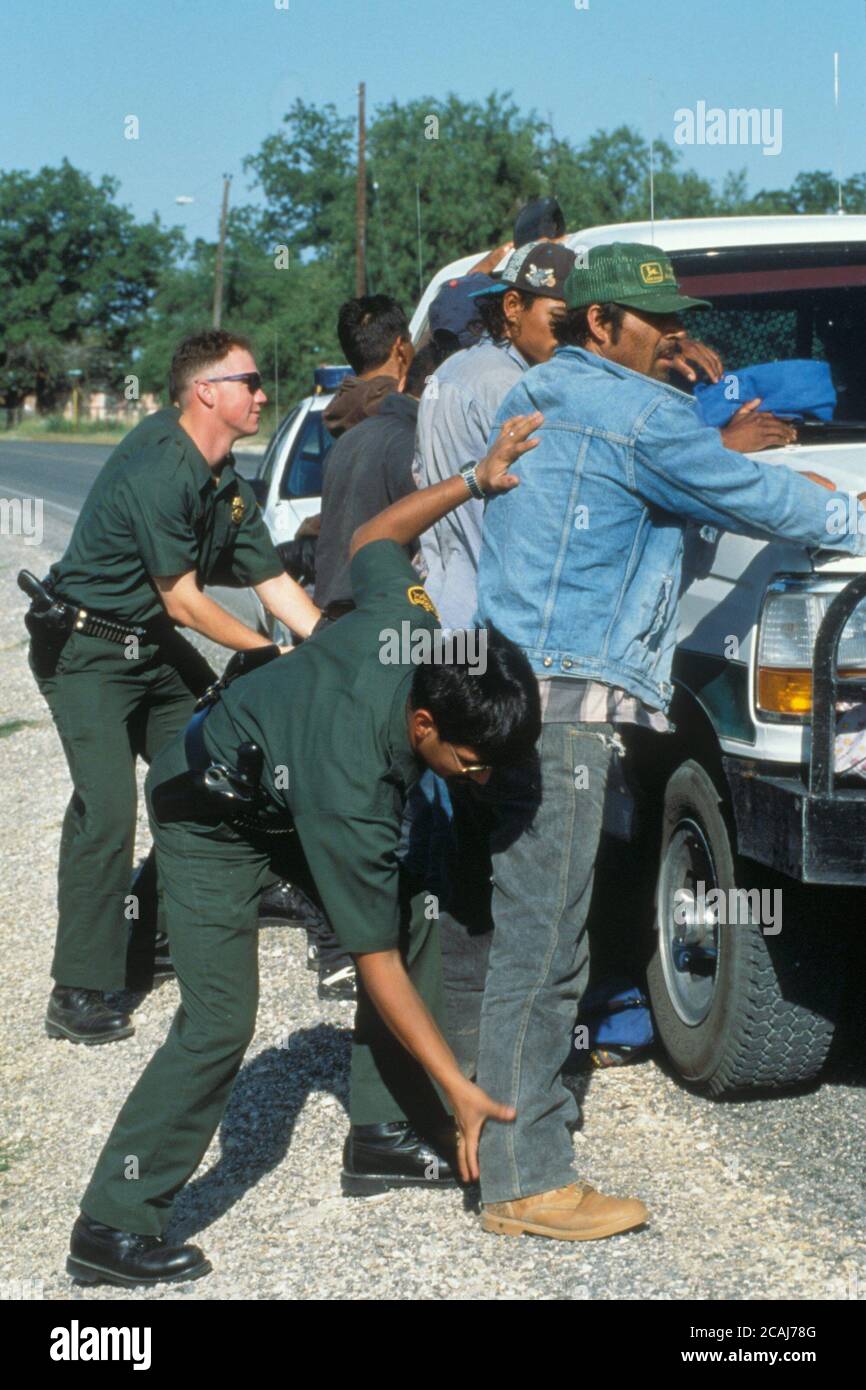Hispanic and Anglo male US Border Patrol agents searching three male ...
