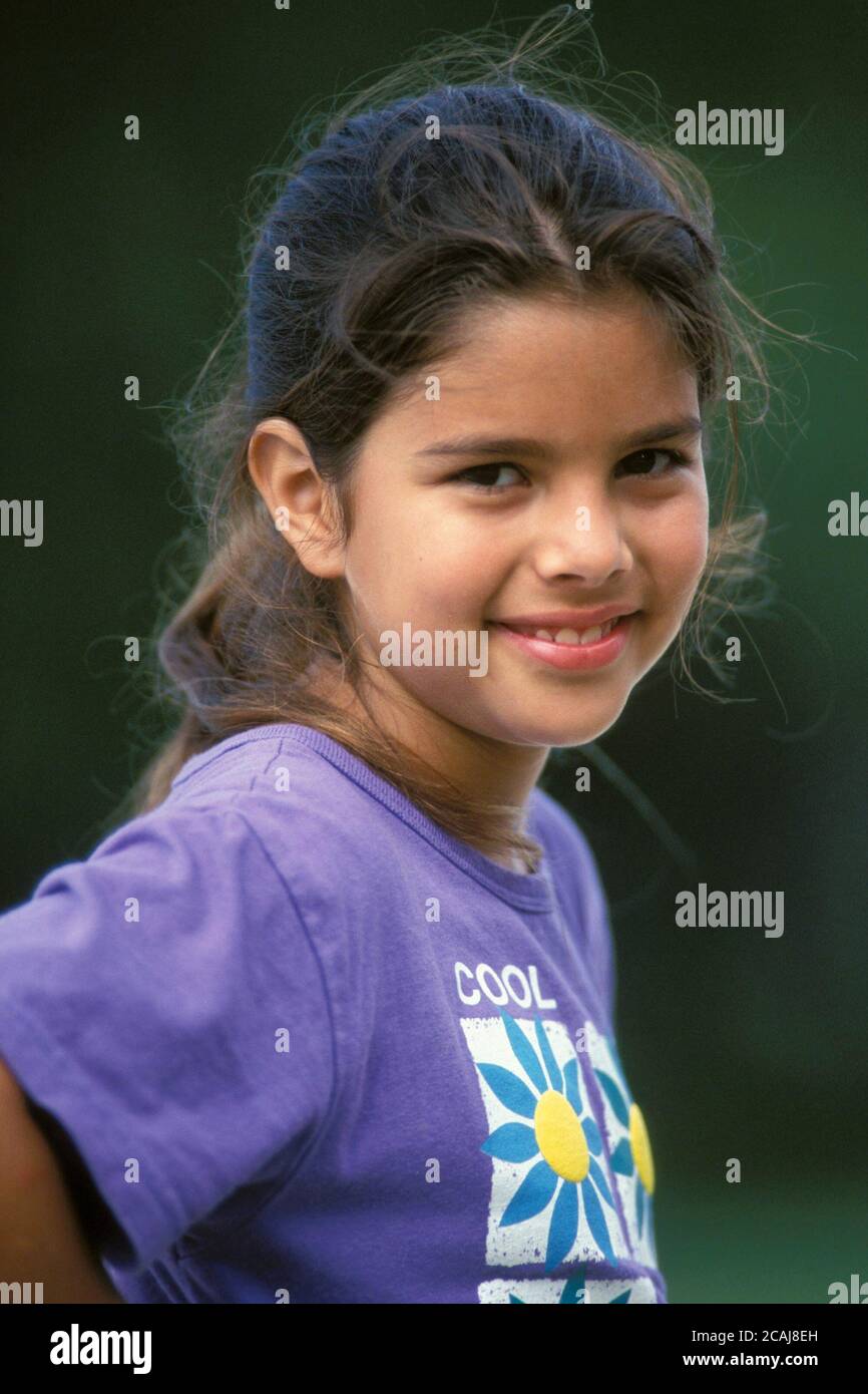 Portrait of eight-year-old Hispanic girl wearing purple tee shirt in ...