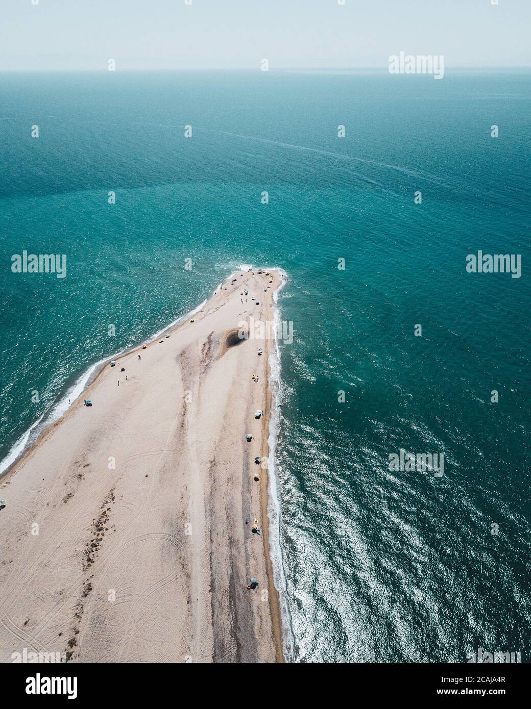Vertical aerial view of turquoise ocean wave reaching the coastline ...