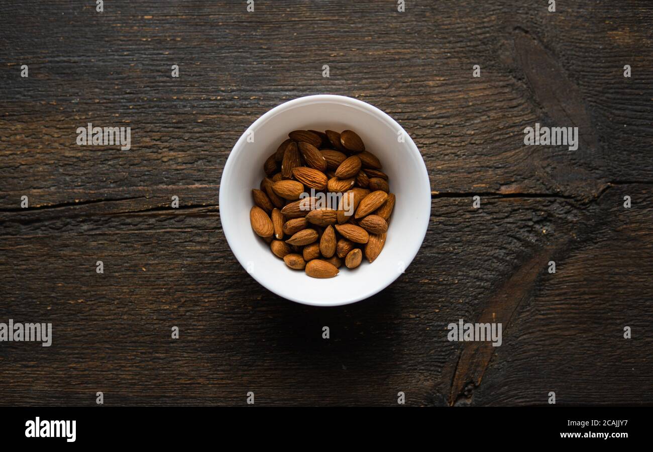 Almonds in a small plate on a vintage wooden table. Almond is a healthy ...