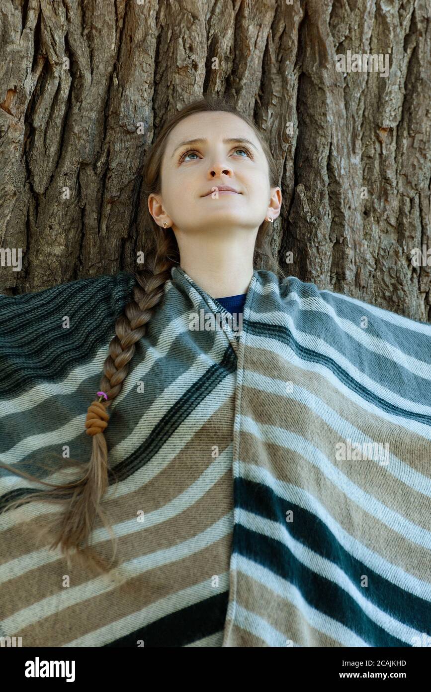 Young woman leaned her back against the trunk of a large tree. Unity ...