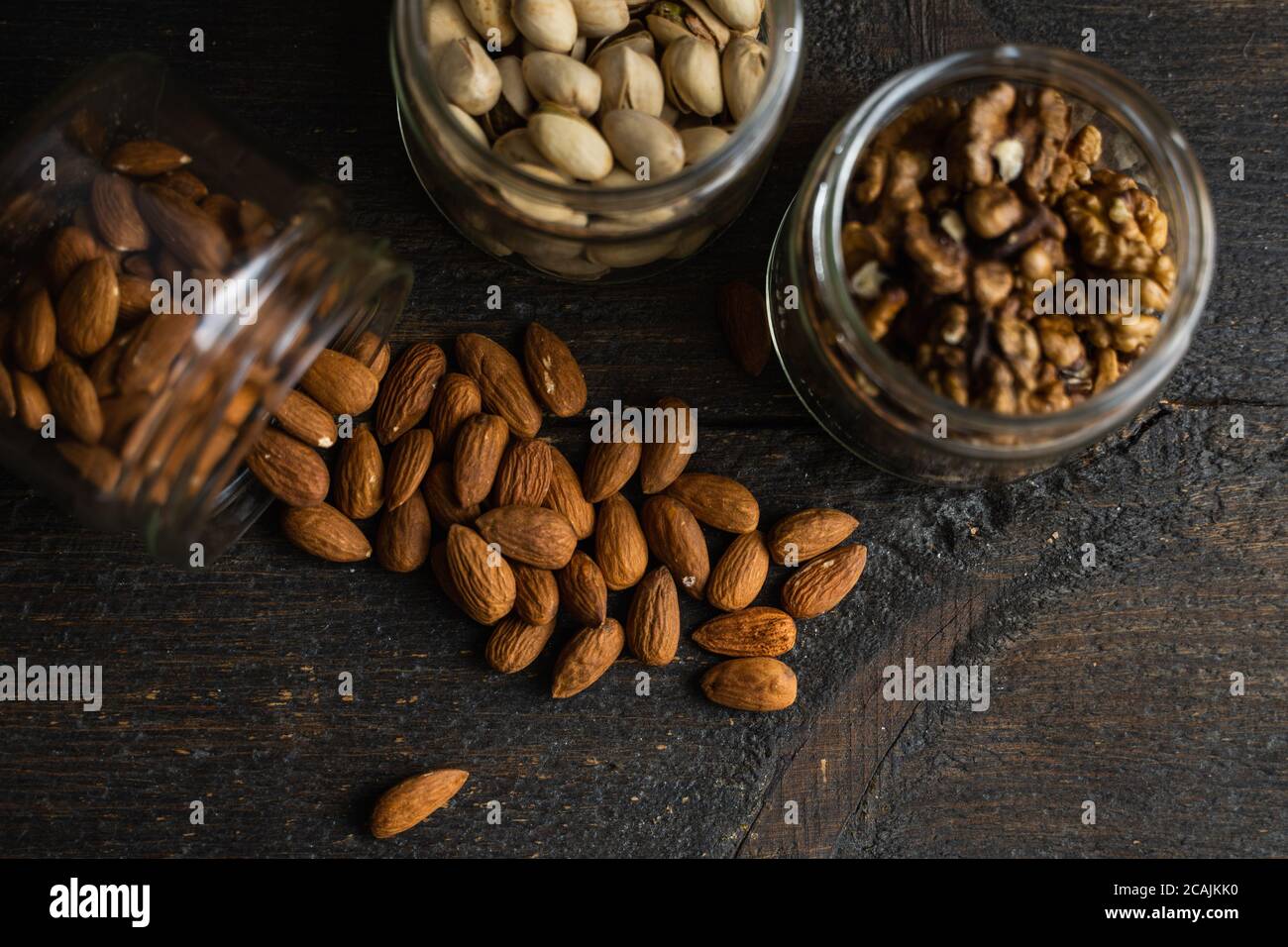 Almonds scattered on the wooden vintage table from a jar. Almond is a ...