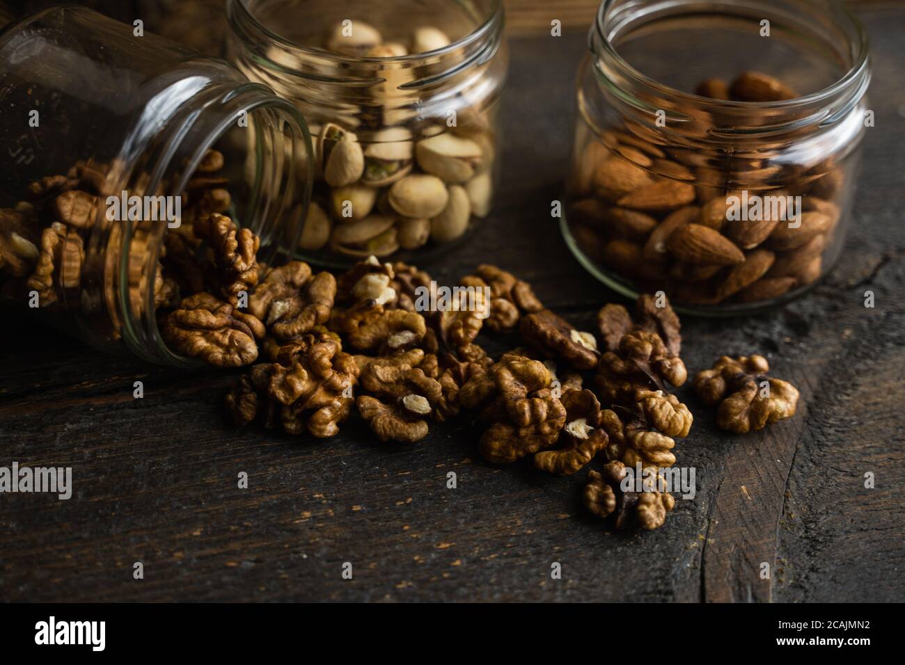 Walnut scattered on the wooden vintage table from a jar. Walnut is a ...