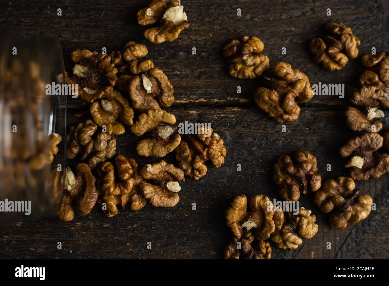 Walnut scattered on the wooden vintage table from a jar. Walnut is a ...