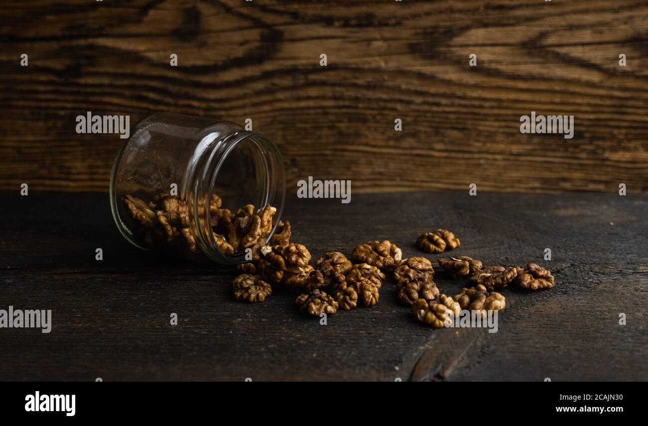 Walnut scattered on the wooden vintage table from a jar. Walnut is a ...