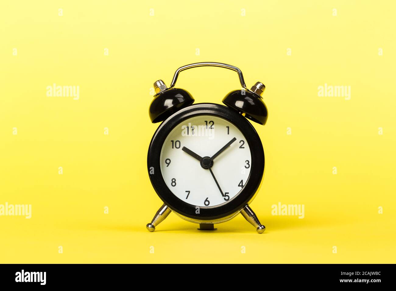 black retro alarm clock on a yellow background, concept of time, daily ...