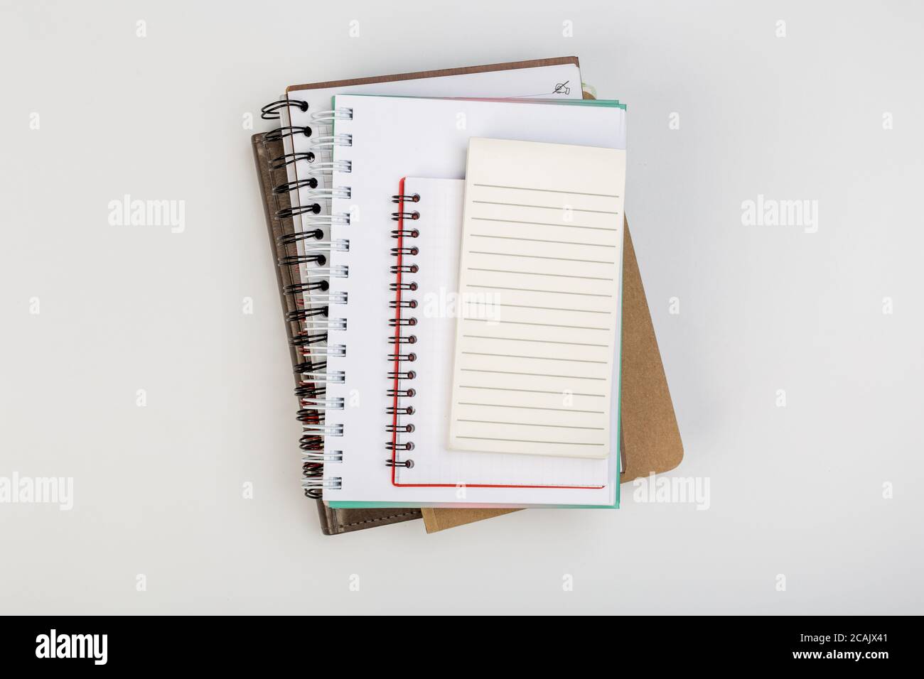 a stack of several spiral school notebooks lies on a white table with a ...