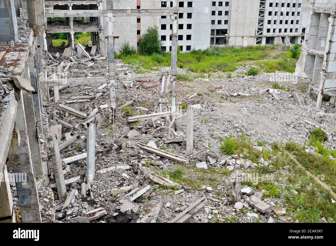 Top view of a pile of gray concrete rubble against the remains of a ...