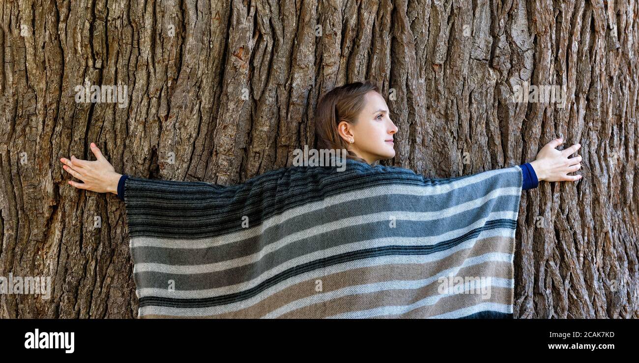 Young woman hugging the trunk of a large tree. Unity with nature ...
