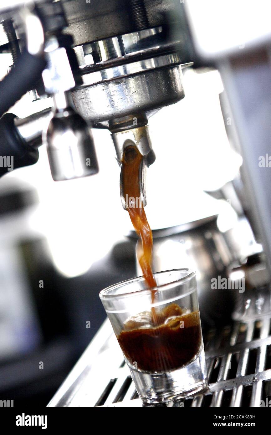 Vertical closeup shot of coffee machine brewing fresh espresso in glass ...